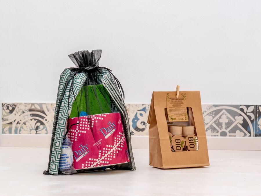 Uma sacola de presentes e uma sacola de papel castanho com um prendedor de roupa numa parede azulejada.