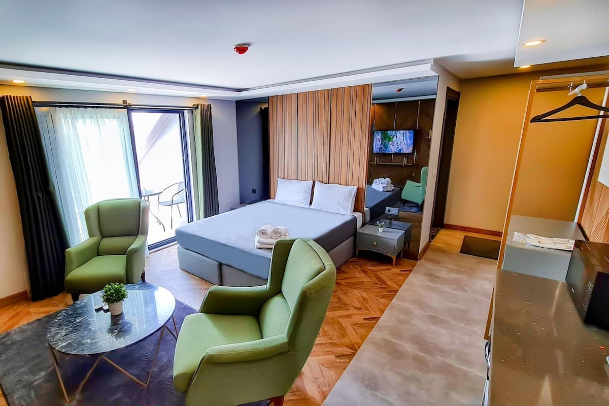 Quarto de hotel com cama, duas cadeiras, uma mesinha, televisão e guarda-roupa.