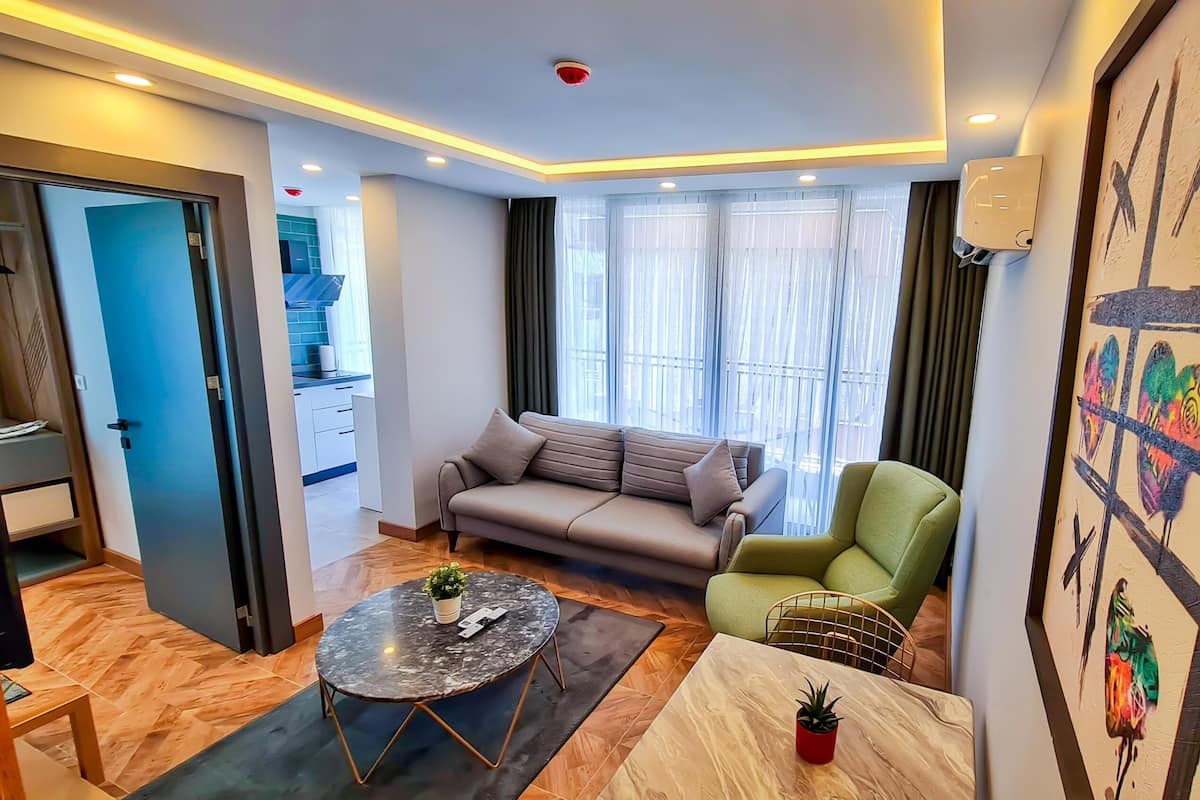 Uma sala de estar moderna com um sofá, uma poltrona verde, uma mesa de centro e uma pintura na parede.