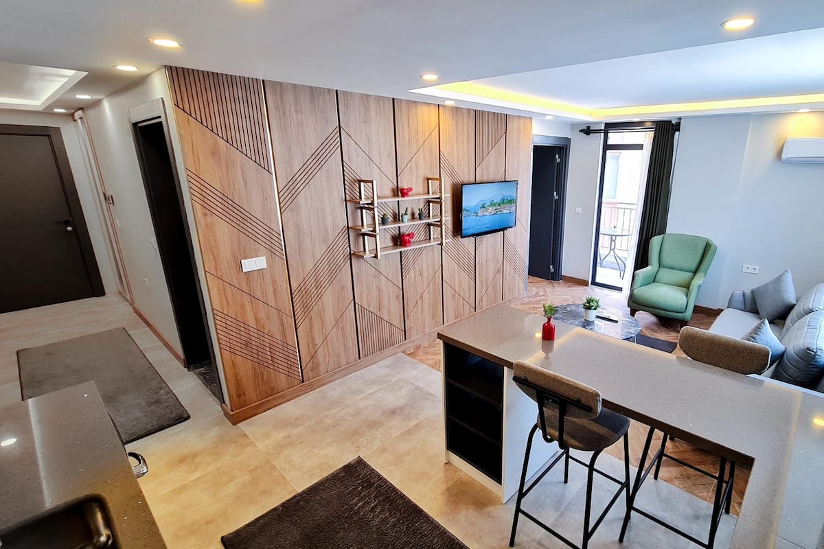 Uma sala de estar moderna com uma televisão, uma poltrona verde e um sofá.