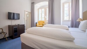 Quarto de hotel com cama, televisão, escrivaninha e cadeira.