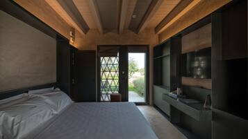 Quarto moderno com uma cama grande, uma escrivaninha embutida e vista através de uma porta de vidro.
