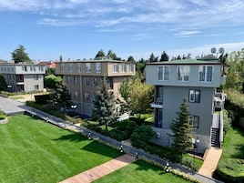 Um complexo residencial com edifícios de apartamentos modernos, um gramado bem cuidado e céu claro.