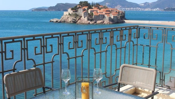 Varanda com mesa e cadeiras com vista para a costa e edifícios numa pequena ilha.