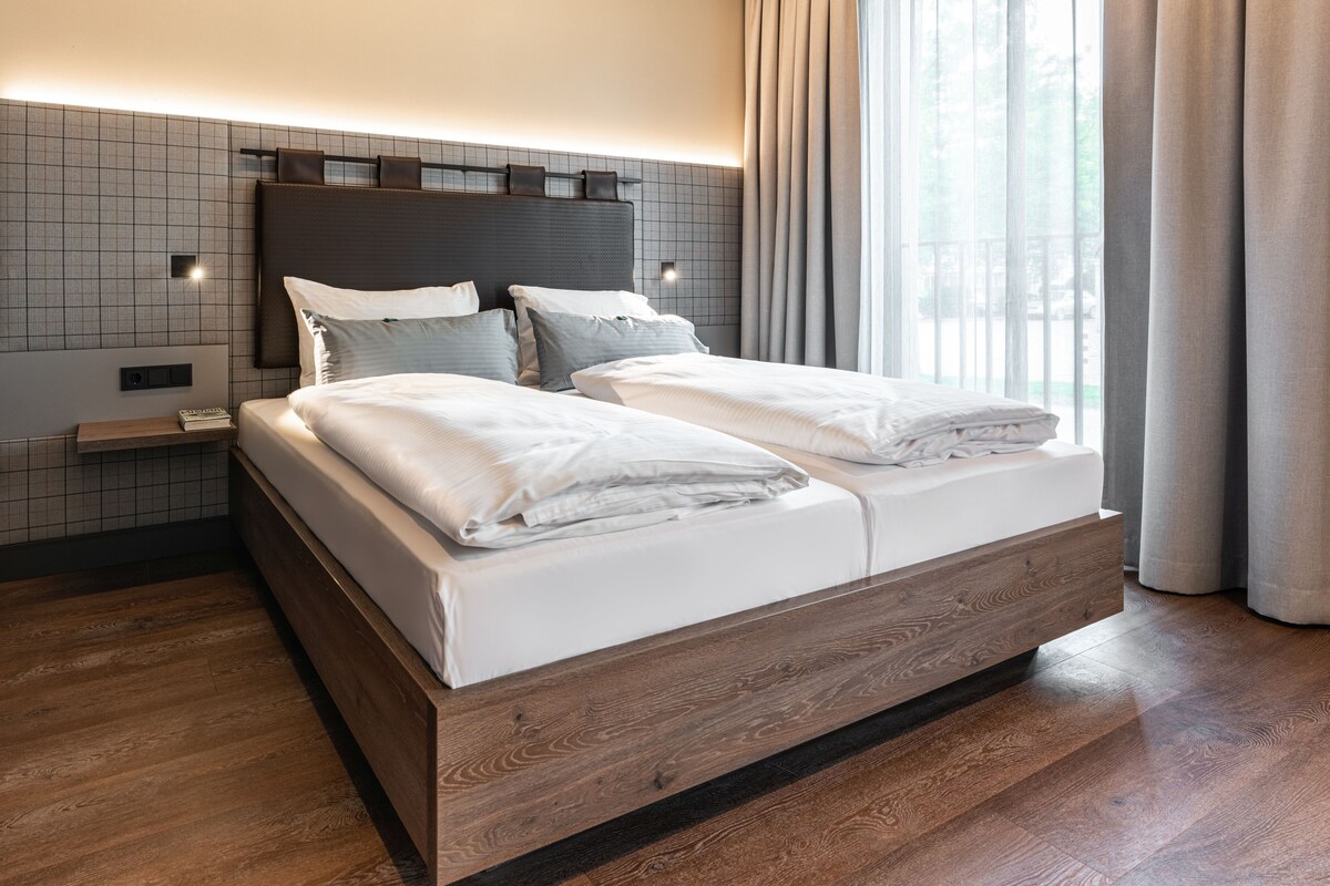 Quarto moderno com uma cama grande, uma mesa de cabeceira e cabeceira com iluminação embutida.