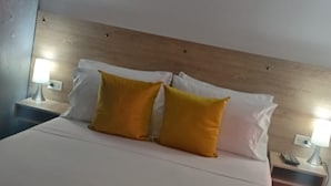 Quarto de hotel com uma cama grande, duas mesas de cabeceira e cabeceira de madeira.
