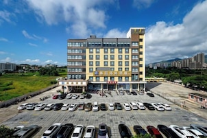 Um hotel com vários andares e um estacionamento na frente.