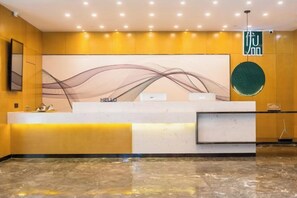 Balcão de recepção com um letreiro 'HELLO', uma obra de arte abstrata moderna e um elemento decorativo circular na parede.