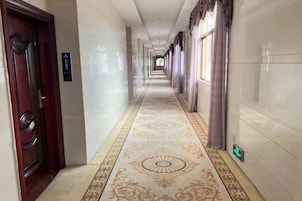Corredor de hotel com carpete estampado, portas e um longo hall.