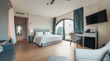 Quarto de hotel moderno com uma cama, uma mesa, uma TV e uma varanda com vista.