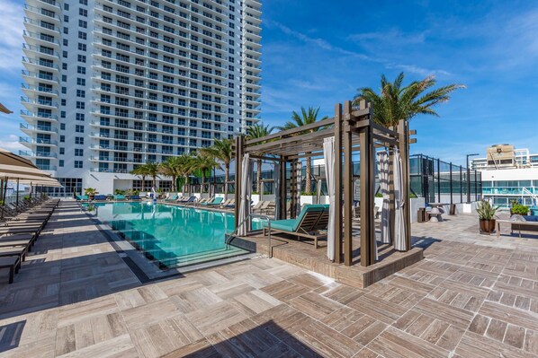 Uma área de piscina no terraço, com espreguiçadeiras e um pérgola.