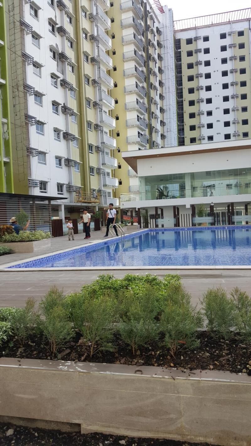Um edifício residencial com várias varandas, piscina e fachada de vidro moderna.