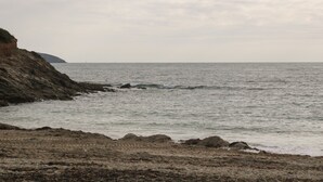 Paisagem costeira com terreno rochoso e vista para o mar.