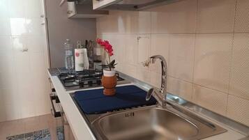 Cozinha moderna com pia de aço inoxidável, fogão a gás e um tapete azul sobre a bancada.