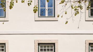 Um edifício com várias janelas, toldo verde sobre a entrada e calçada de pedra.