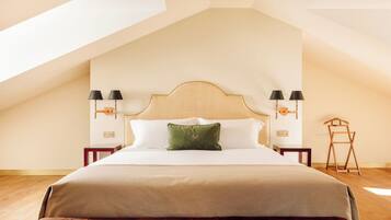 Quarto com uma cama grande, duas luminárias de cabeceira, um painel de cabeceira de madeira e uma cadeira de madeira.