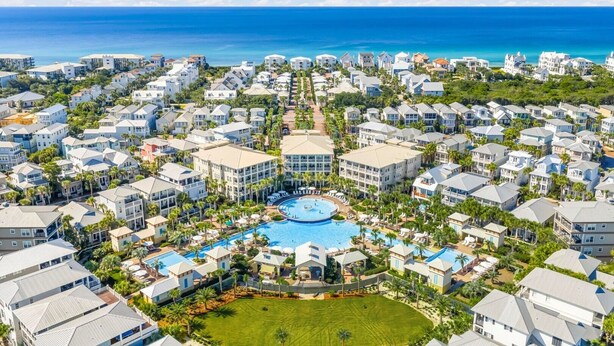 Um resort com vários edifícios, uma piscina central e vista para o oceano.