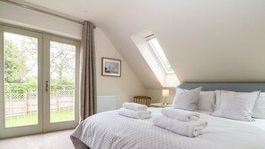 Quarto com cama grande, claraboia, vista para o quintal e um quadro na parede.