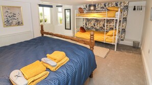 Um quarto com uma cama de solteiro, uma cama beliche e um radiador.