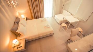 Quarto de hotel com cama, mesa de cabeceira, abajur e uma pequena escrivaninha com cadeira.