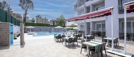 Uma área à beira da piscina com mobiliário de exterior e piscina.