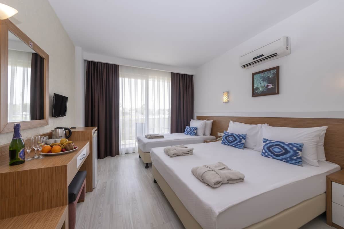Quarto de hotel com duas camas, uma escrivaninha com espelho, televisão e ar condicionado.