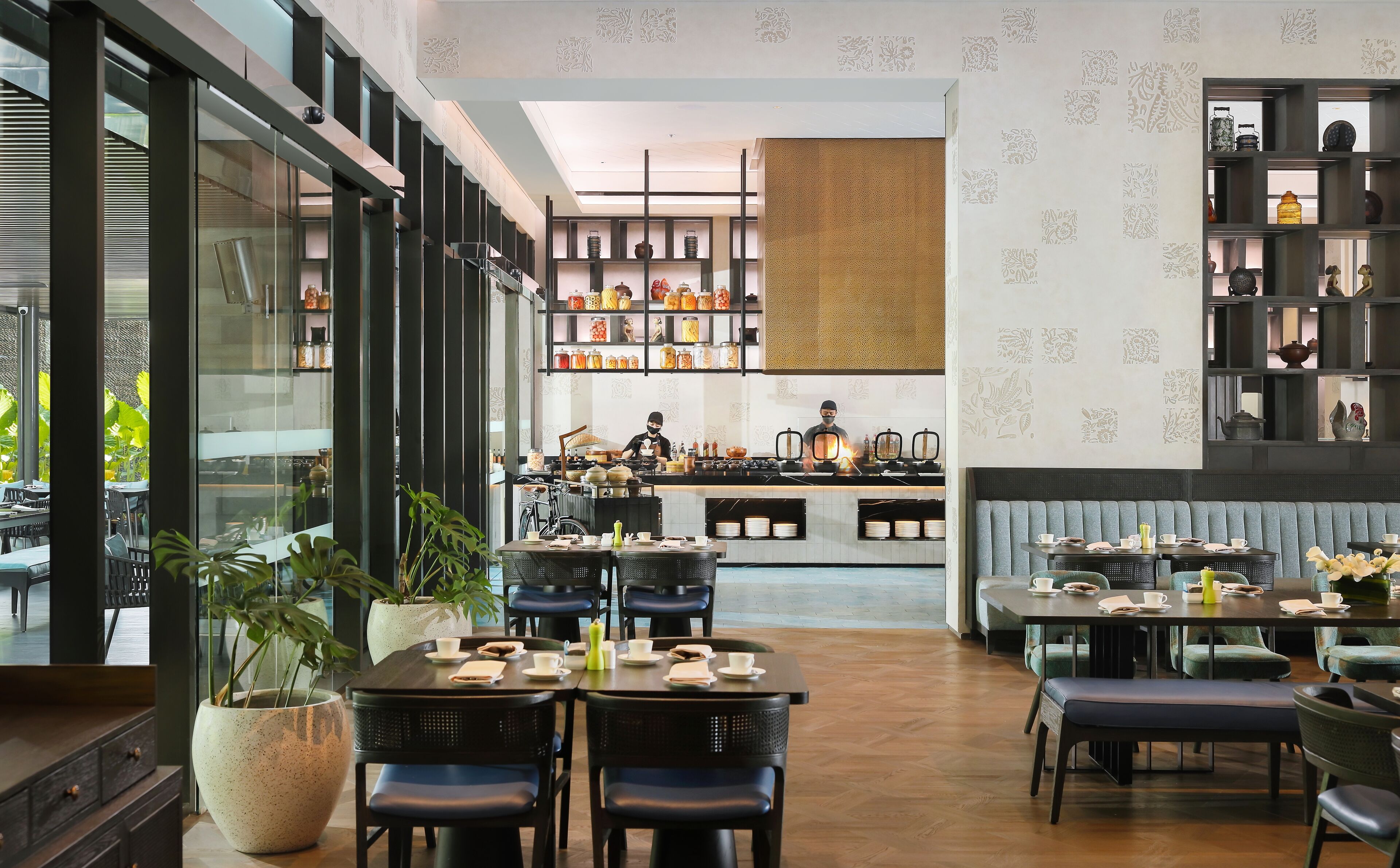 Um restaurante moderno com cozinha central, área de refeições com mesas e cadeiras, e padrões decorativos nas paredes.