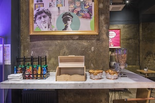 Uma área de bar com balcão de madeira, garrafas de bebidas e doces.