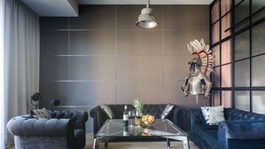Uma sala de estar moderna com uma mesa de centro de vidro, dois sofás e um capacete decorativo na parede.