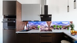 Cozinha moderna com eletrodomésticos embutidos, uma janela grande com vista para a cidade e uma fruteira no balcão.