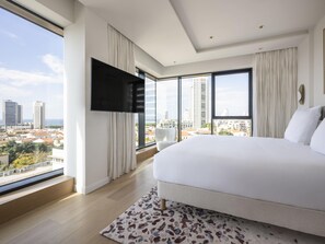 Quarto de hotel moderno com uma cama grande, televisão de tela plana e vista para a cidade.