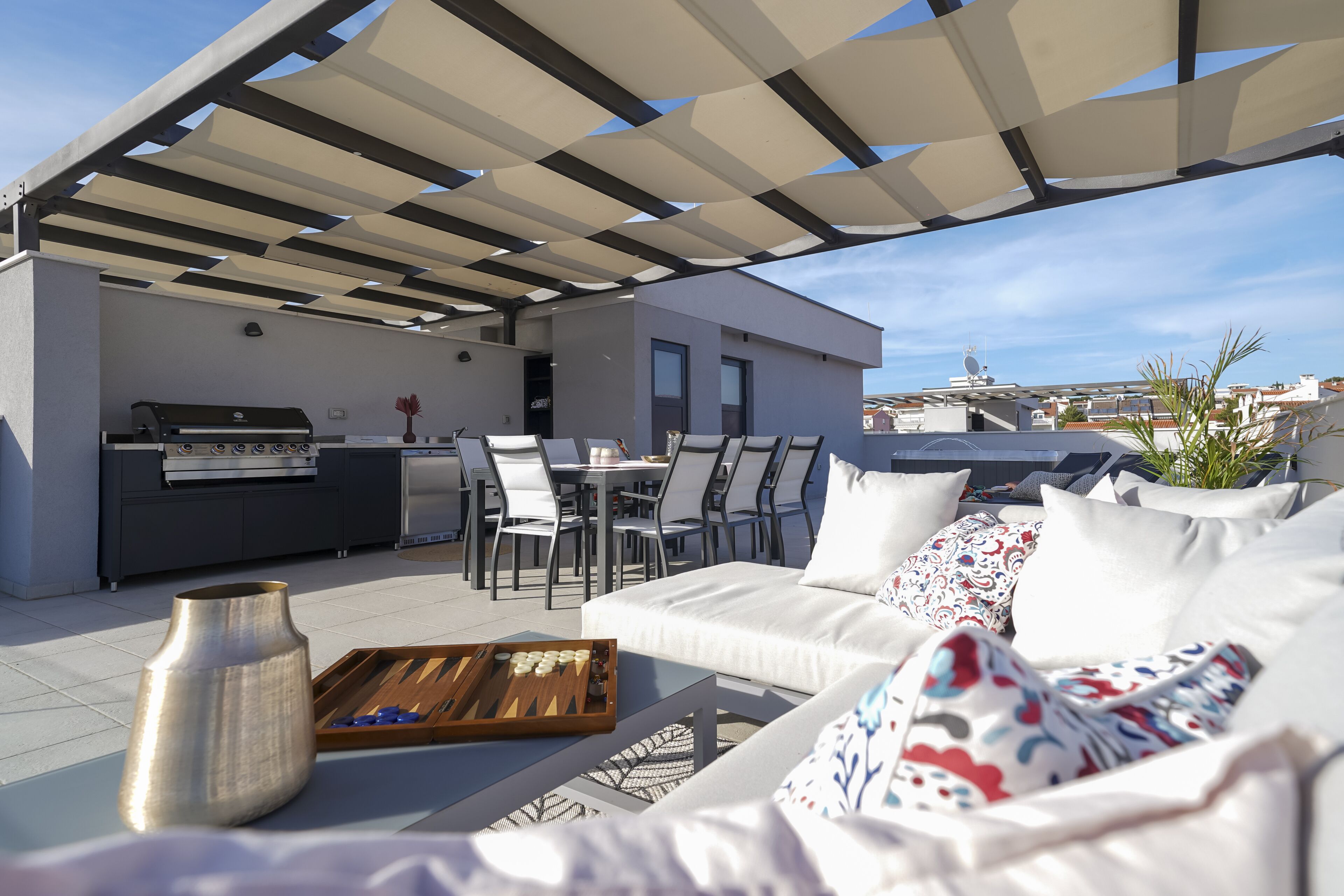 Terraço no terraço com churrasqueira, área de estar ao ar livre e vista da cidade.