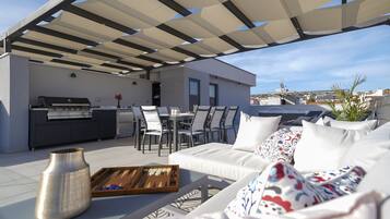 Terraço no terraço com churrasqueira, área de estar ao ar livre e vista da cidade.