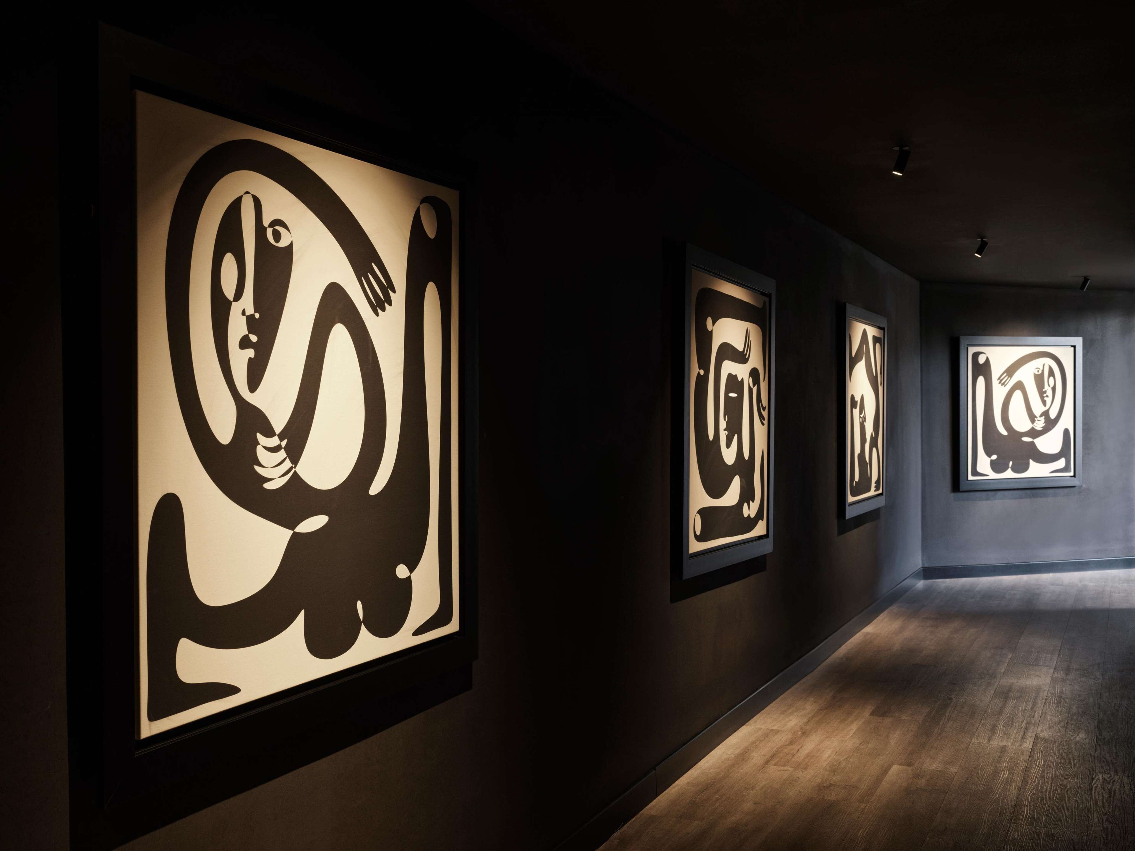 Uma galeria com arte abstrata emoldurada nas paredes.