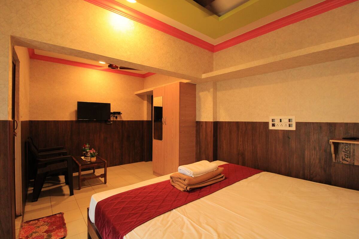Quarto de hotel com cama, televisão, escrivaninha e cadeira.