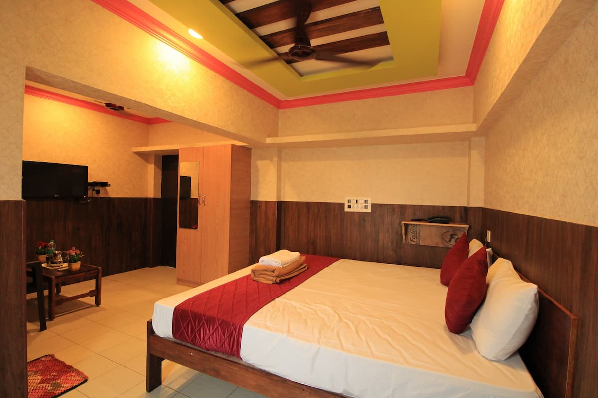 Quarto com uma cama, televisão, mesa de cabeceira de madeira e esquema de cores vermelho e branco.