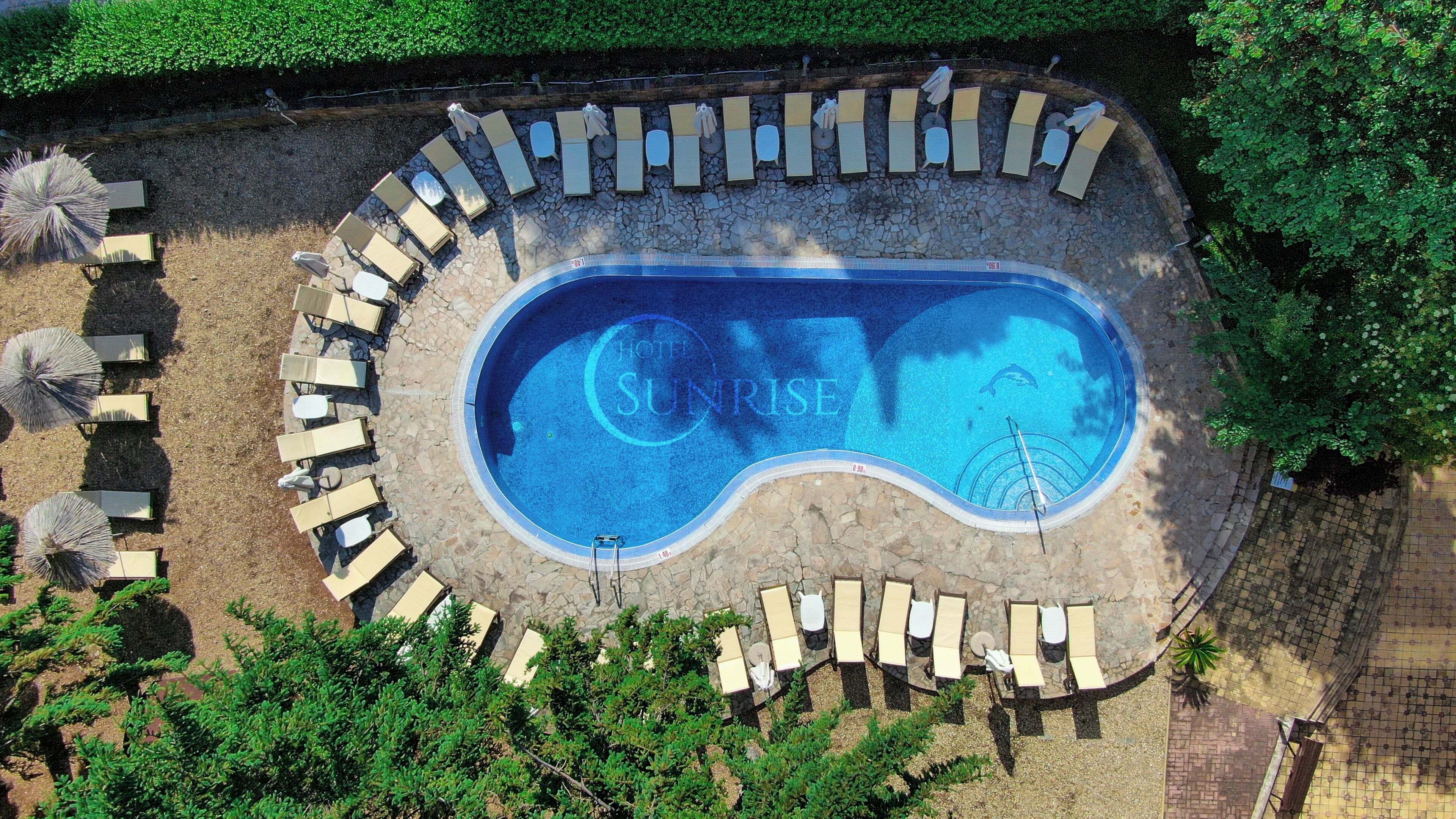 Piscina com espreguiçadeiras e uma parede de pedra ao redor.