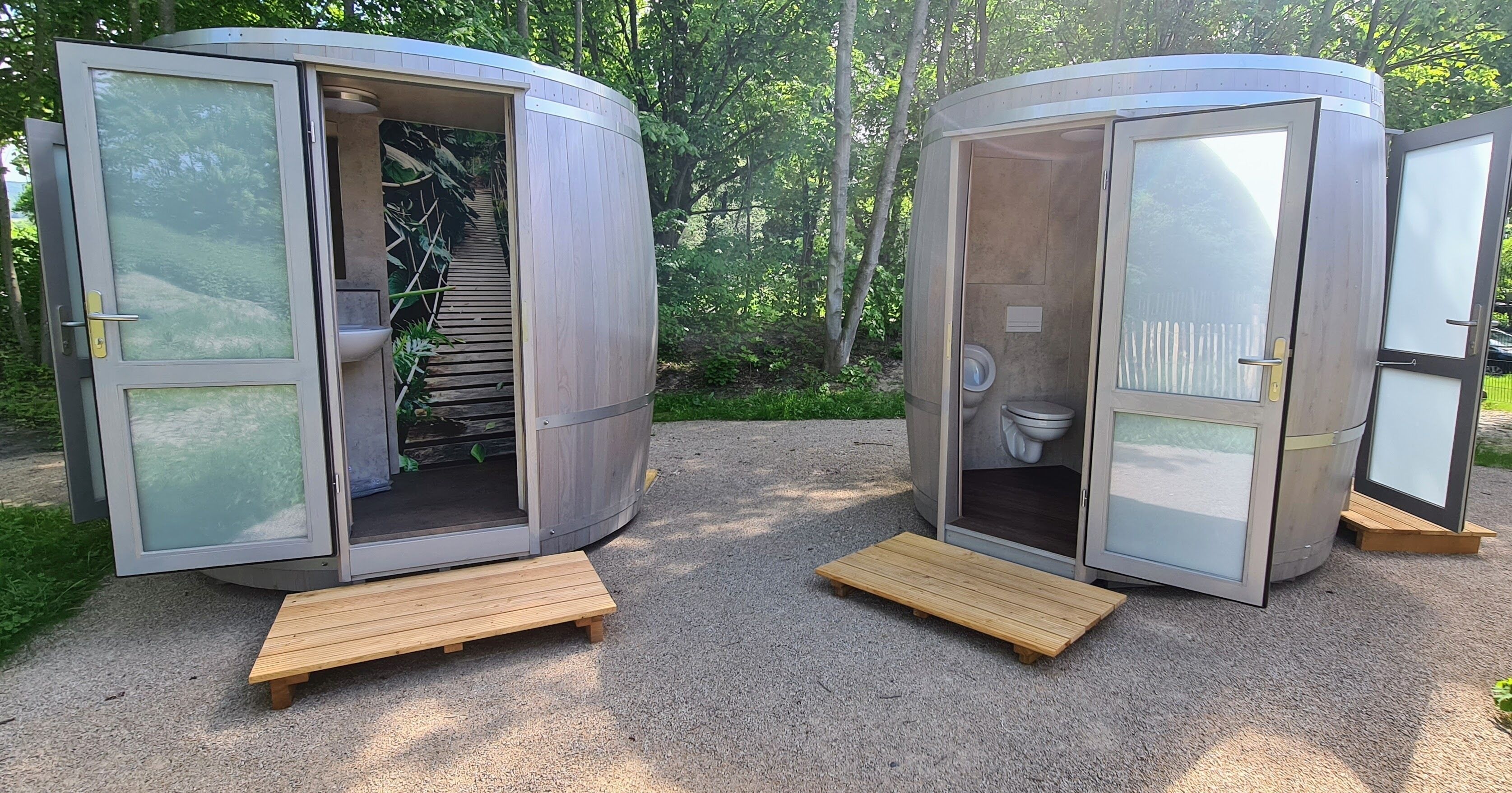 Duas estruturas cilíndricas portáteis, cada uma com portas abertas e um degrau de madeira para entrar.