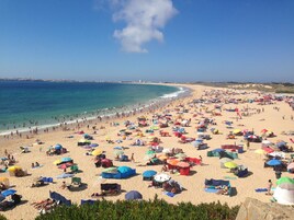 Uma praia lotada, com muitos guarda-sóis e toldos.
