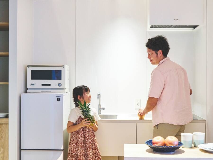 Uma cozinha moderna com micro-ondas integrado, frigorífico e lava-loiça.