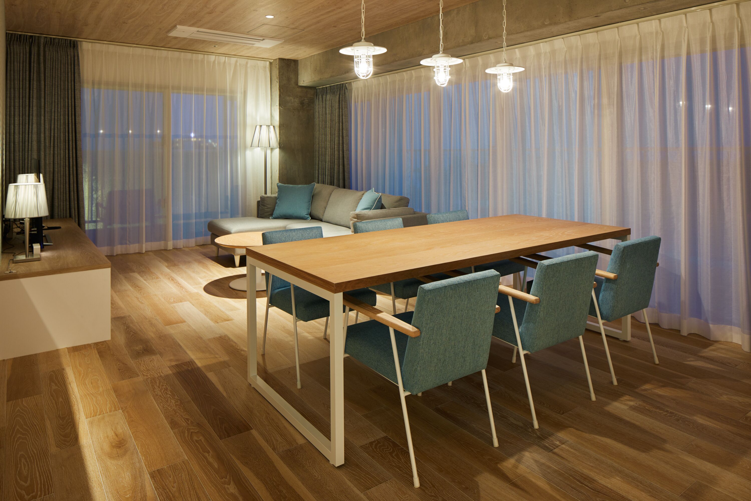 Uma área de refeições moderna com uma mesa de madeira e cadeiras estofadas em azul.