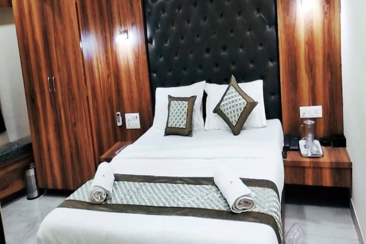 Quarto de hotel com cama grande, guarda-roupa de madeira e ventoinha no teto.