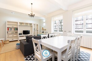 Uma sala de estar moderna com área de jantar, televisão e lustre.