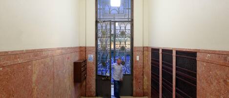 Um corredor com piso de azulejos e uma porta com grade de metal.