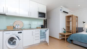 Uma cozinha compacta com máquina de lavar embutida, micro-ondas e armário de madeira.