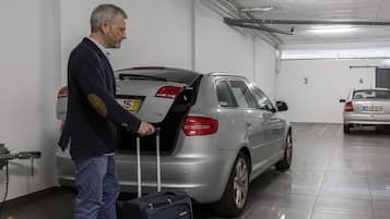 Um homem com uma mala em uma garagem de estacionamento.