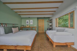 Quarto com duas camas de madeira, uma escrivaninha e um guarda-roupa.