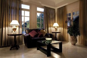 Uma sala de estar com sofá, duas mesas laterais com luminárias, uma mesa de centro e uma planta em vaso.