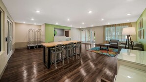 Ampla sala de estar com mesa de jantar de madeira, cadeiras, sofá e mesa de centro de vidro.