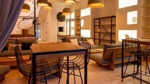 Um interior moderno com área de jantar, mesa de madeira e cadeiras de metal, rodeada por sofás e uma escada.